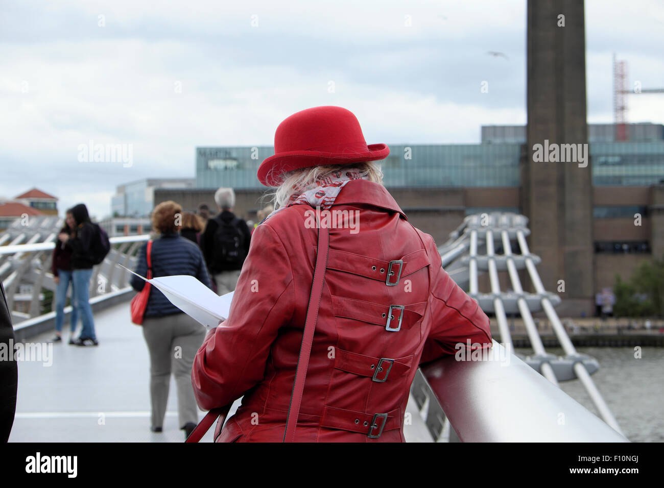 Rear view of tourist in red coat & bowler hat looking at map on the ...