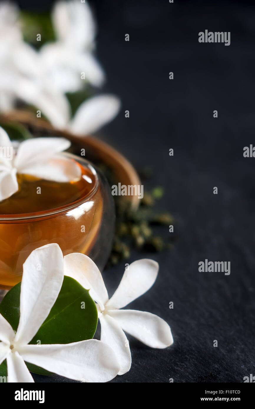 Cup of jasmine tea with bamboo scoop and blossom. Copy space background ...
