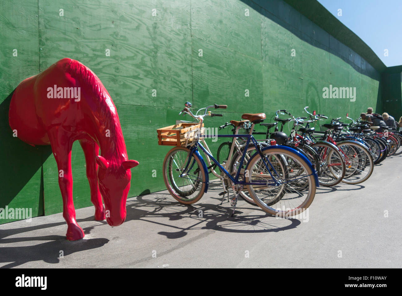 Half of a red horse juts out from green boarding adjacent to a rack of ...