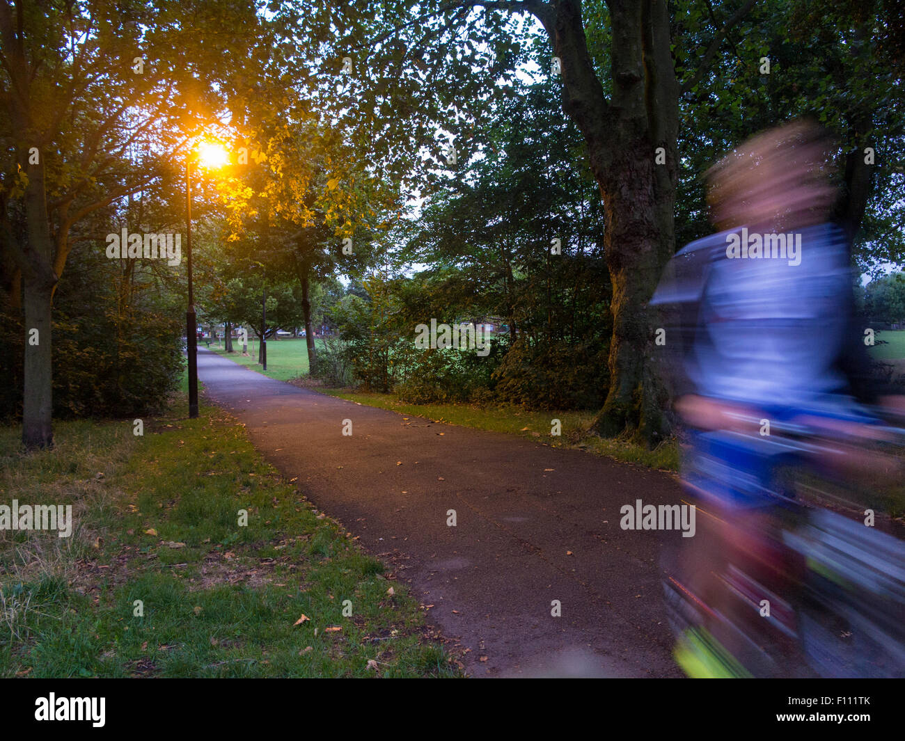 A child cycles his bike in a london park at night with a bright ...