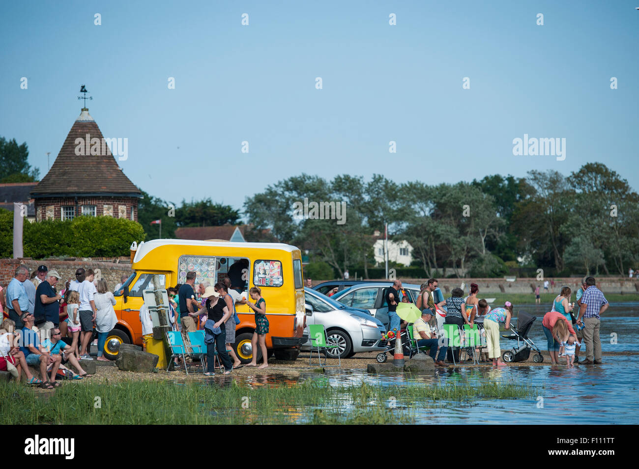 A crowd of hot people queuing around an ice cream on a summer day by ...