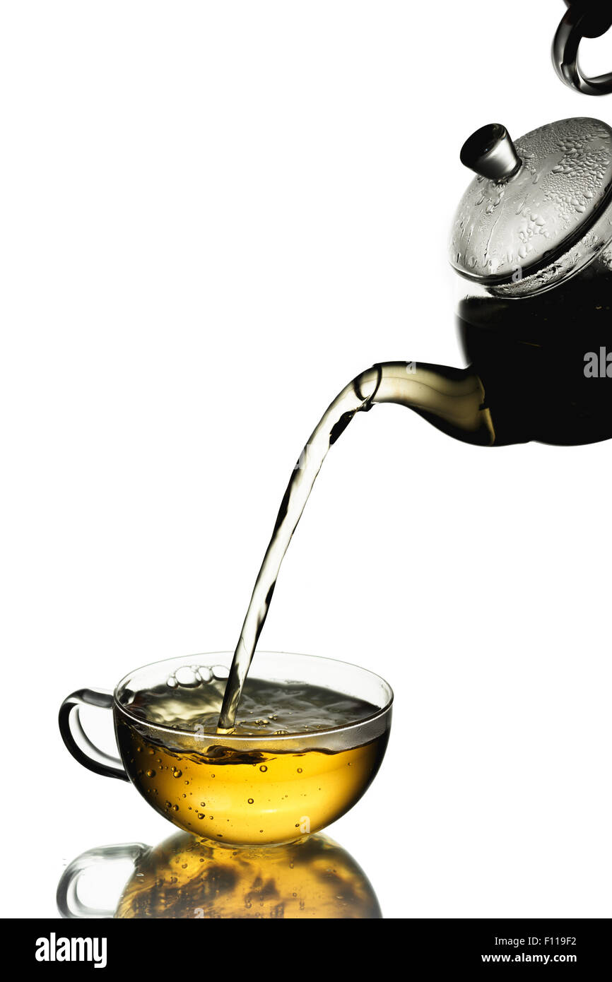 Frozen action of green tea pouring from glass teapot to a glass mug ...