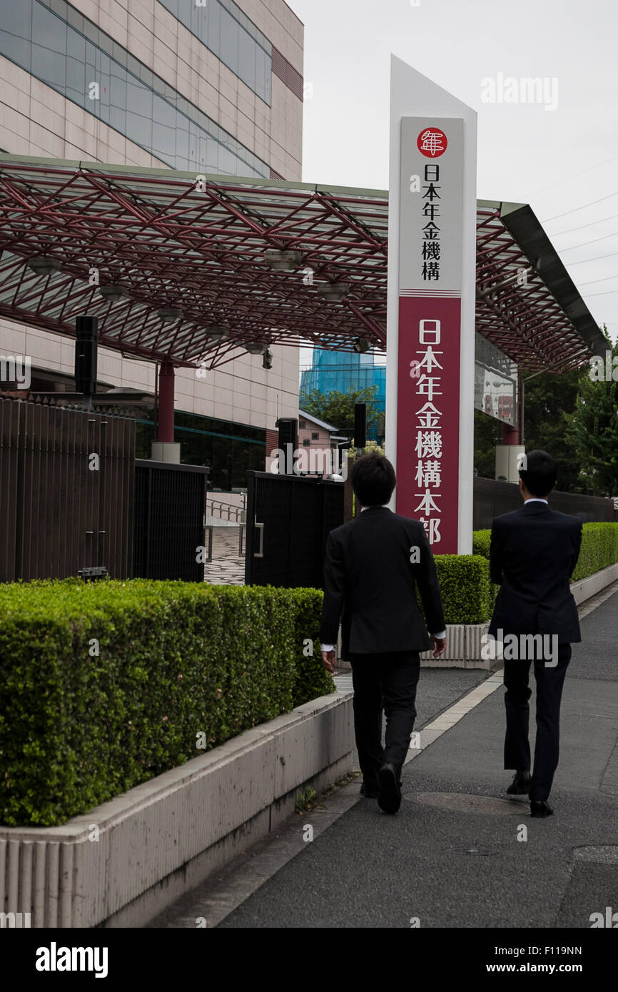 Pedestrians walk pass the Japan Pension Service (JPS) building in Tokyo ...