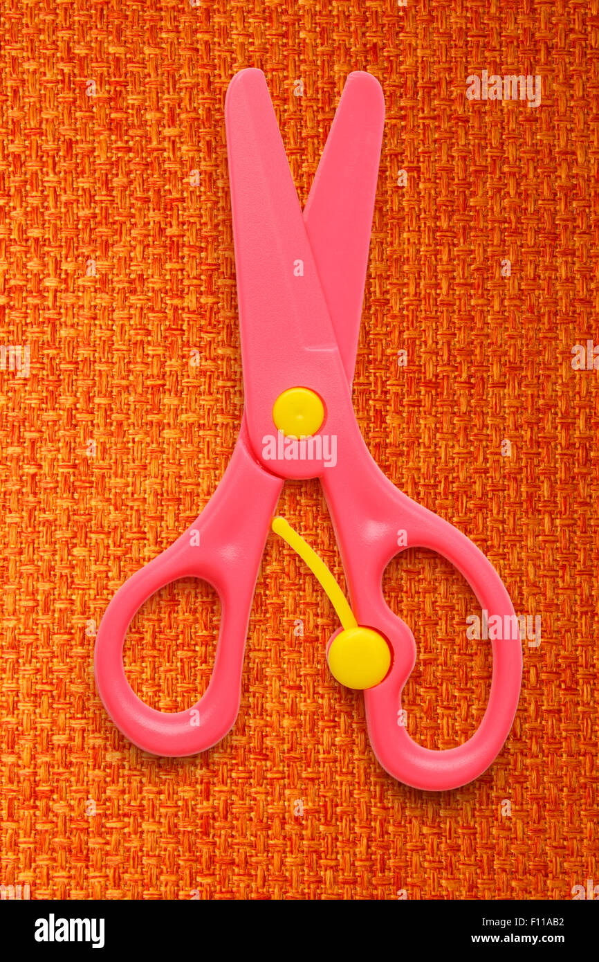Pink safe children scissors on orange background Stock Photo - Alamy