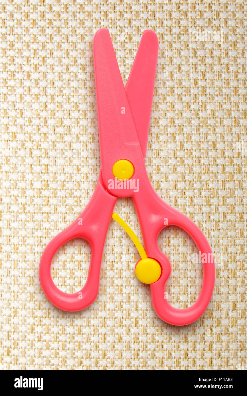 Pink safe children scissors on textile background Stock Photo - Alamy