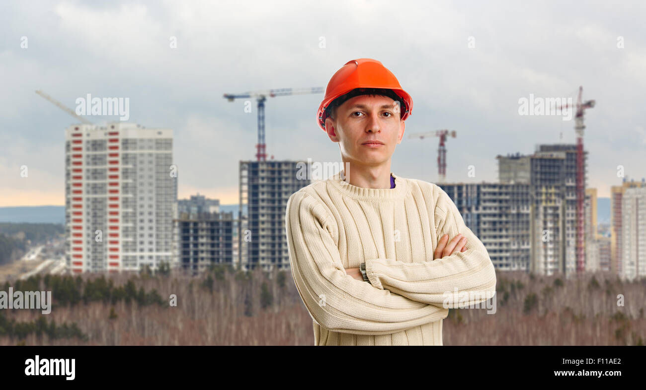 Workman in red helmet on background of buildings under construction and ...