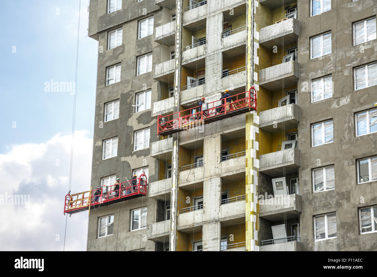 Tall building under construction and workers on platforms Stock Photo ...