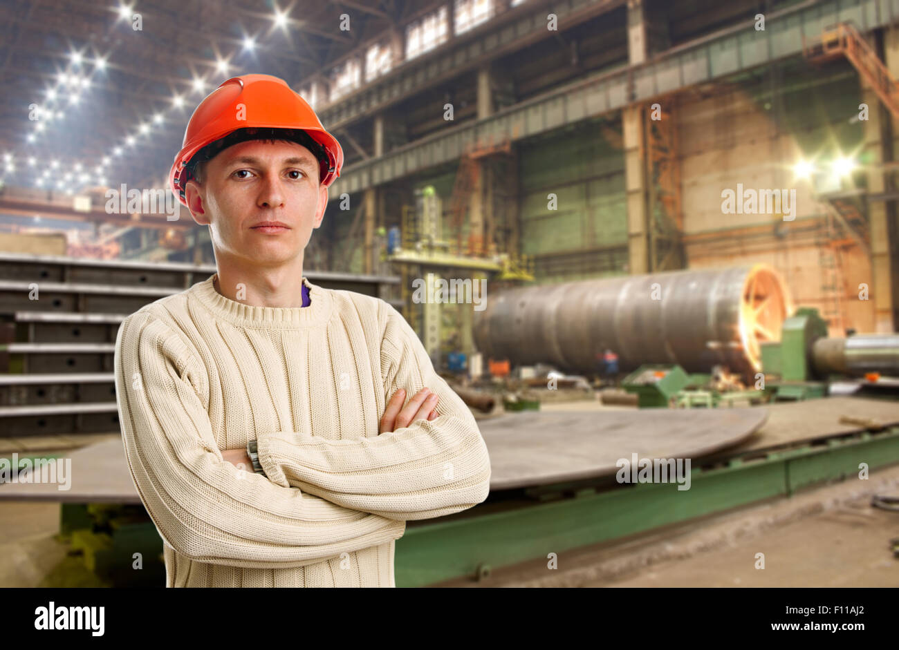 Workman in red helmet in the workshop of machinery plant Stock Photo ...