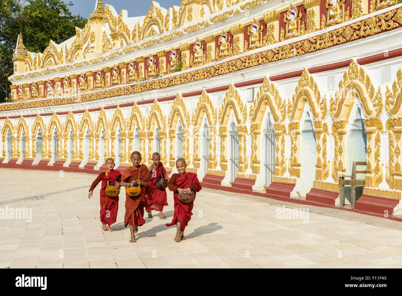 Asian monks-in-training running outside ornate temple Stock Photo - Alamy
