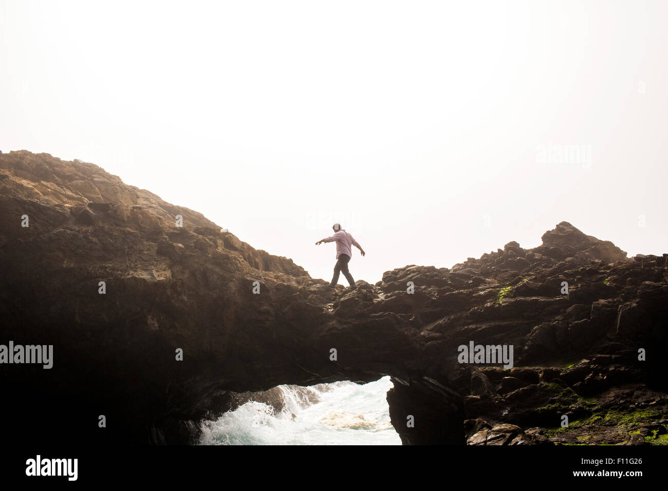 Caucasian man walking on bridge over ocean waves Stock Photo - Alamy