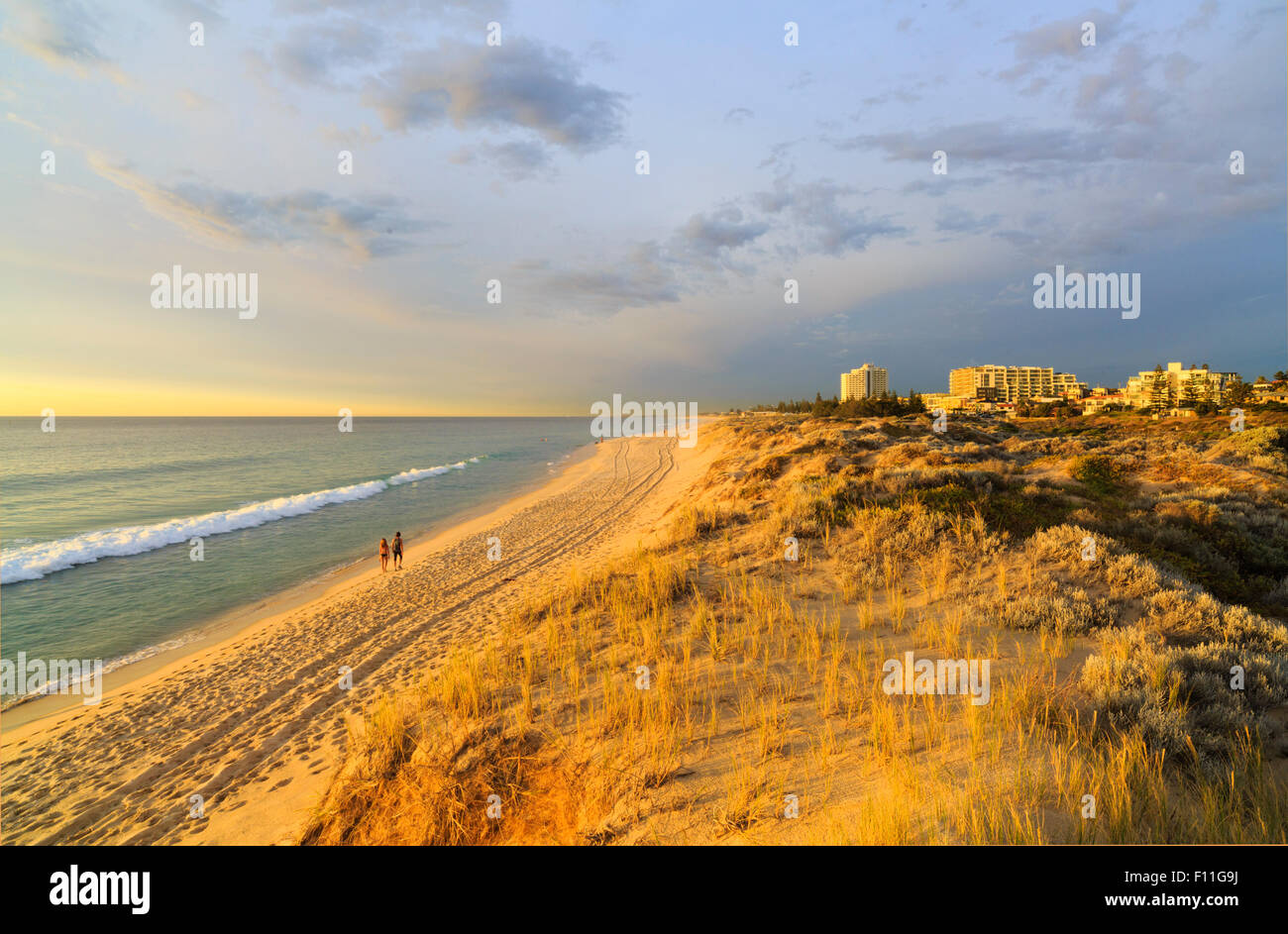 A couple walking along Scarborough Beach in the late afternoon summer ...