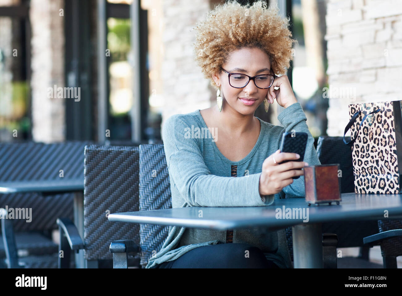 Black woman using cell phone at cafe Stock Photo - Alamy