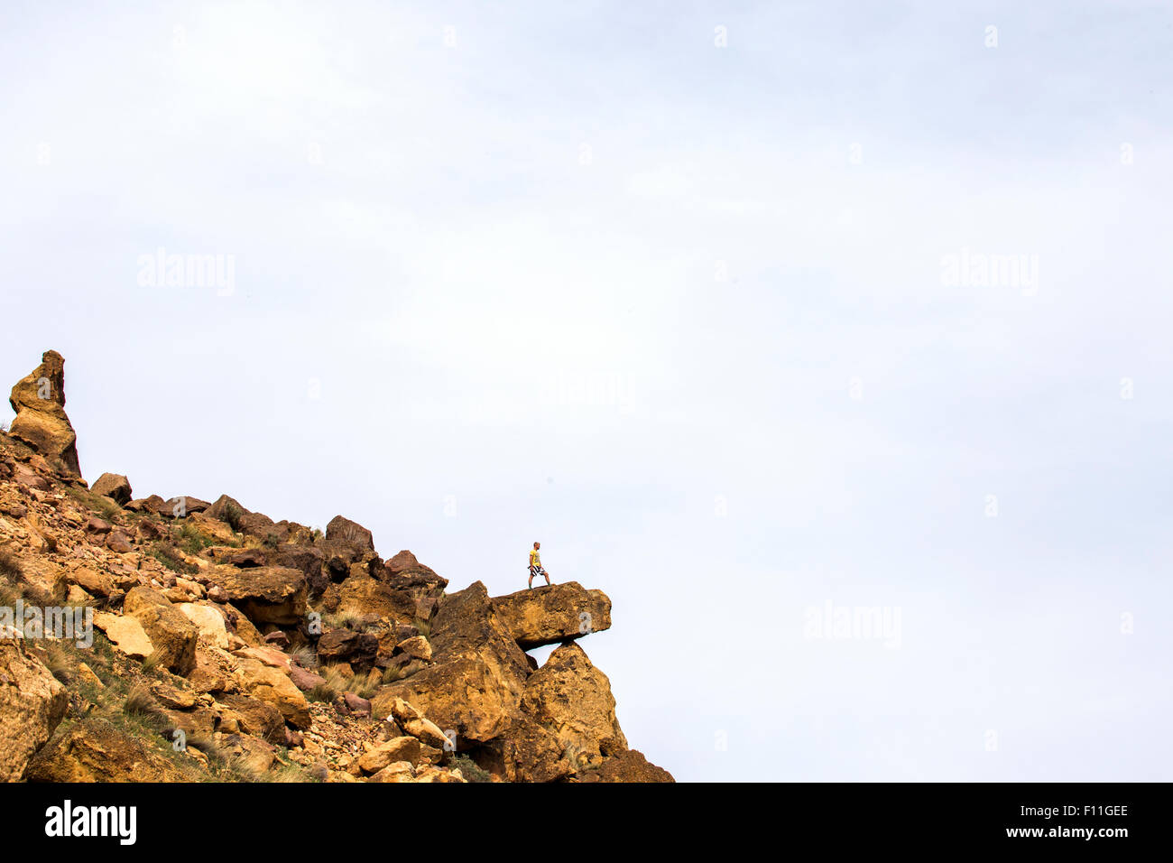 Caucasian hiker standing on sheer cliff boulder, Smith Rock State Park ...