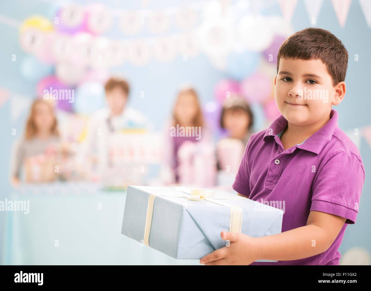 Boy holding wrapped gift at birthday party Stock Photo - Alamy