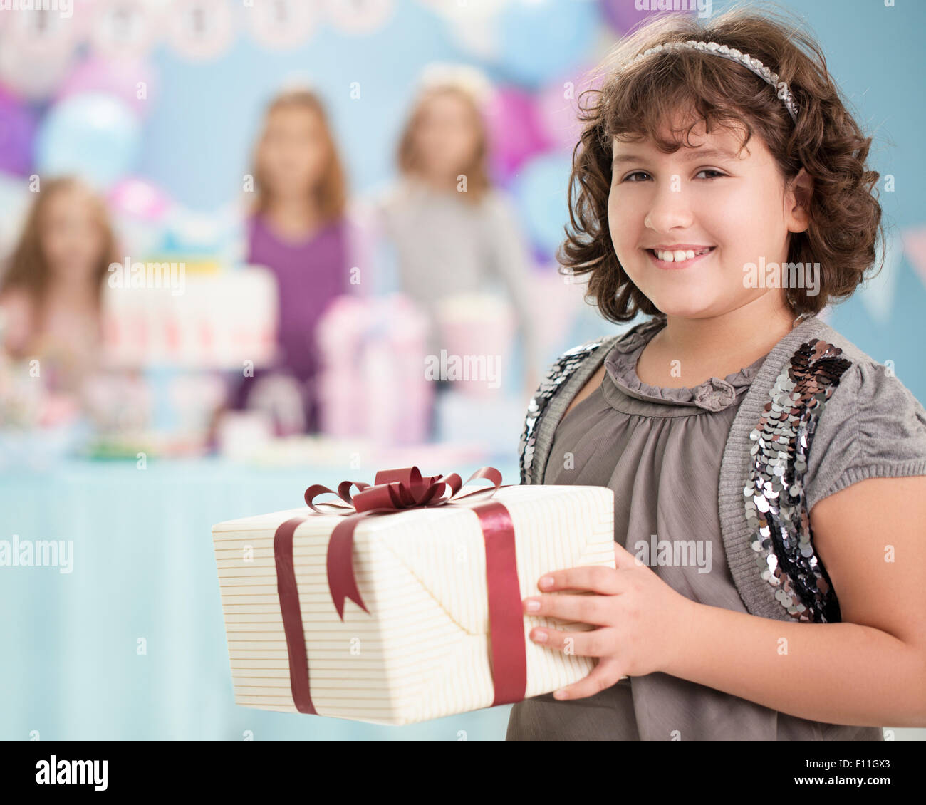 Girl holding wrapped gift at birthday party Stock Photo - Alamy