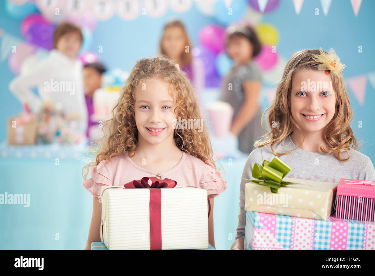 Girls holding wrapped gifts at birthday party Stock Photo - Alamy