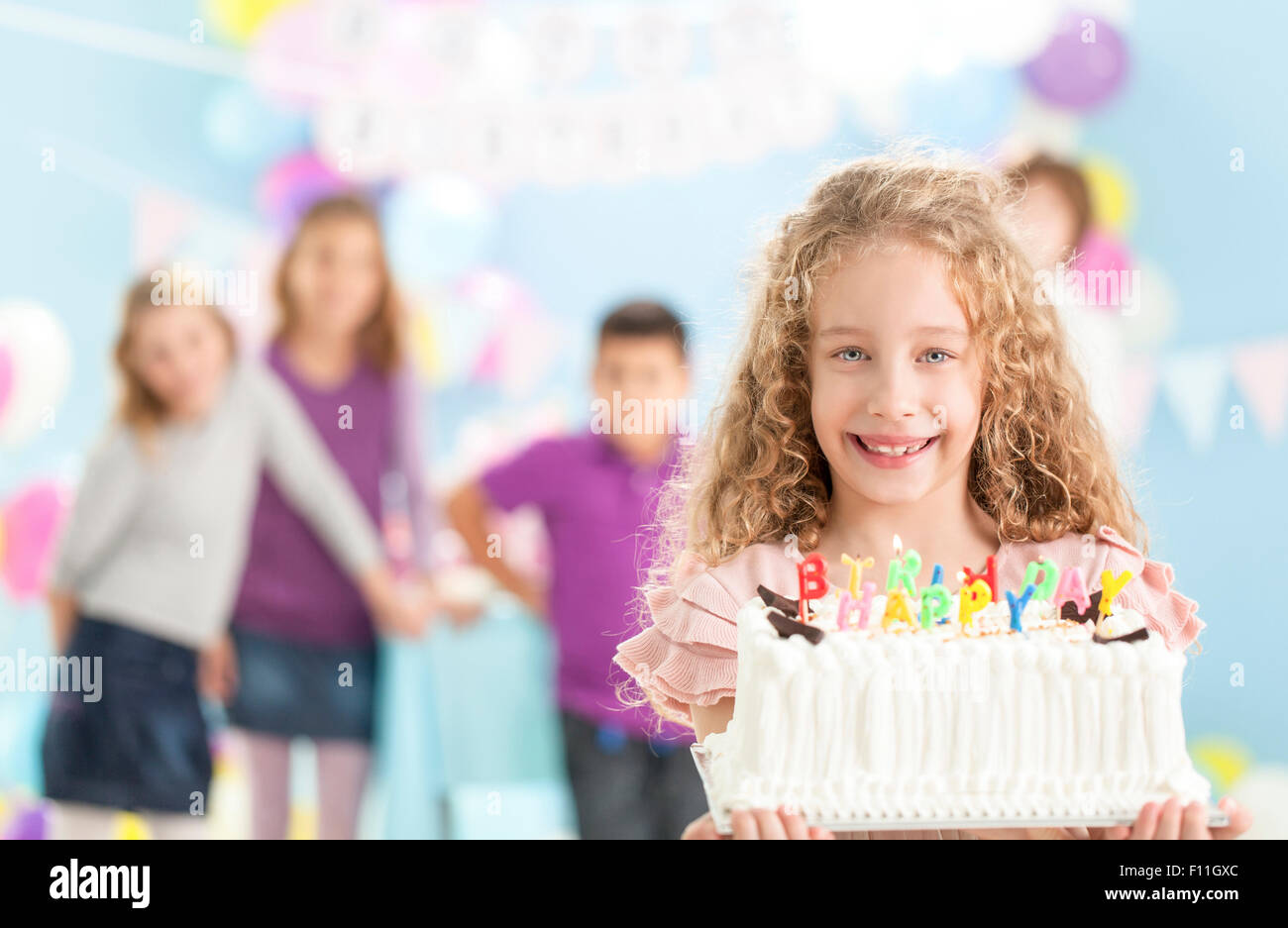 Smiling girl holding birthday cake at party Stock Photo - Alamy