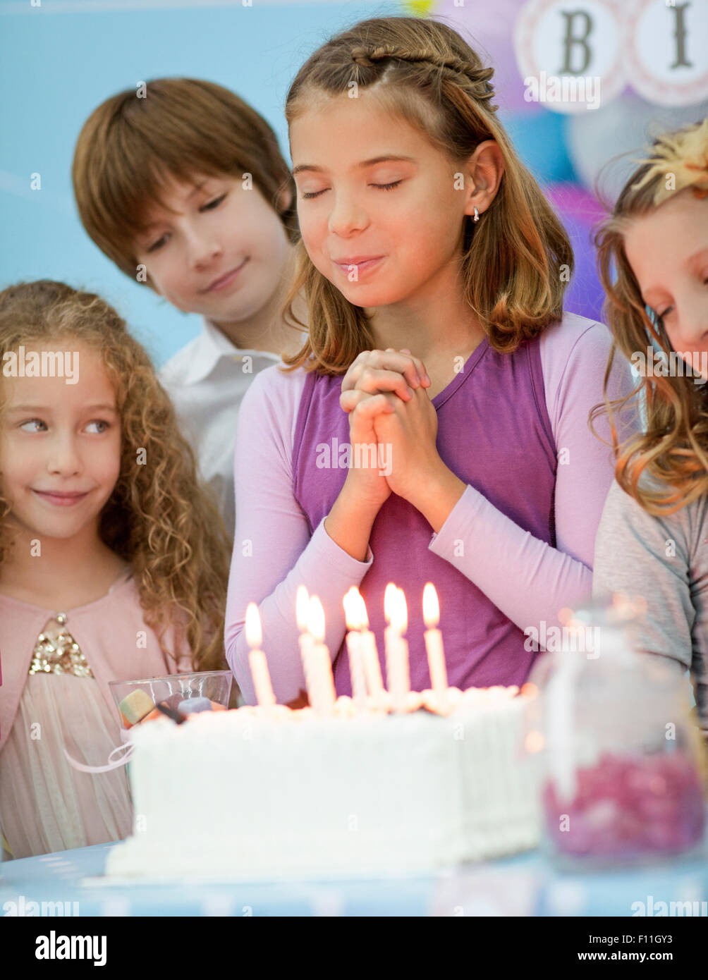 Girl wishing over birthday cake at party Stock Photo - Alamy