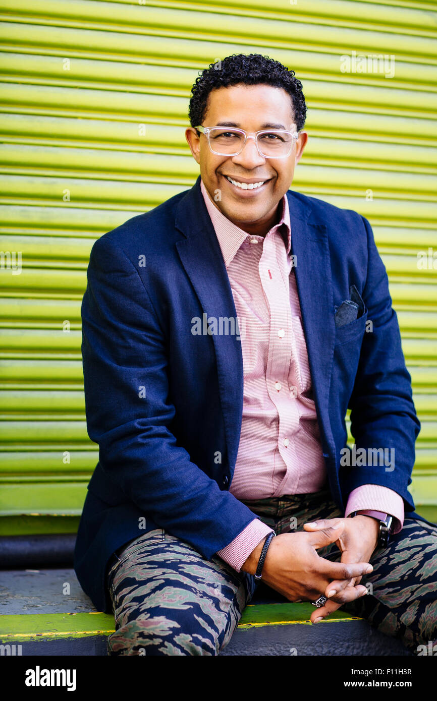 Mixed race businessman sitting at loading dock door Stock Photo - Alamy