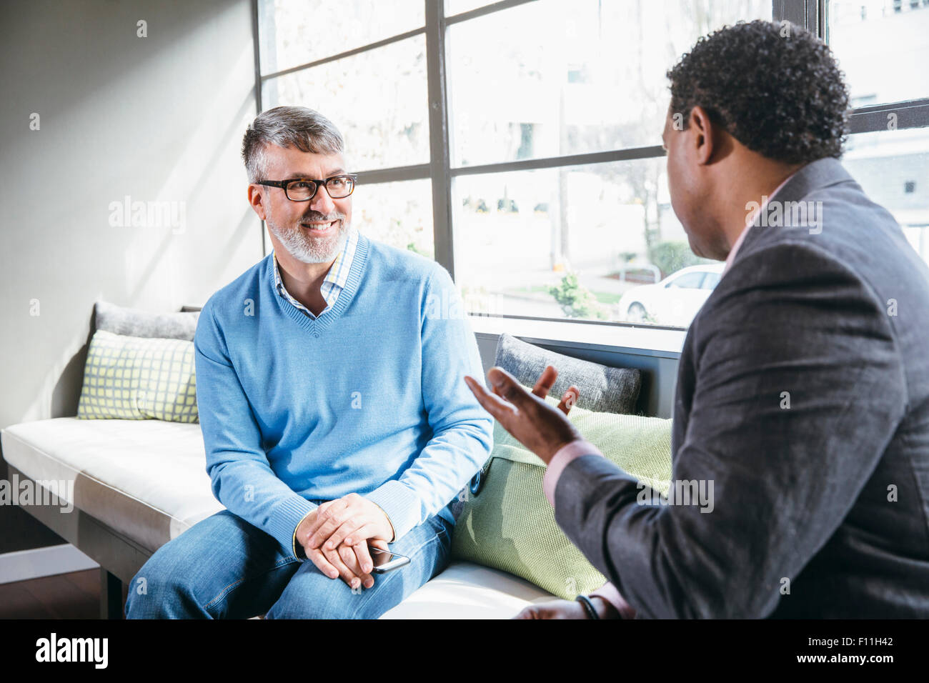 Businessmen talking in office lobby Stock Photo - Alamy