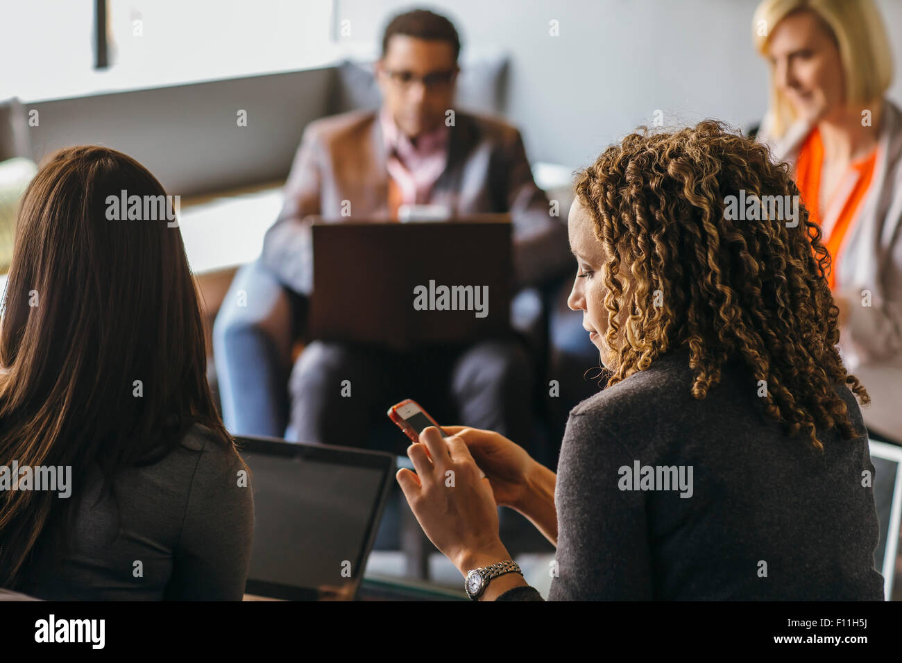 Businesswoman using cell phone in office meeting Stock Photo - Alamy