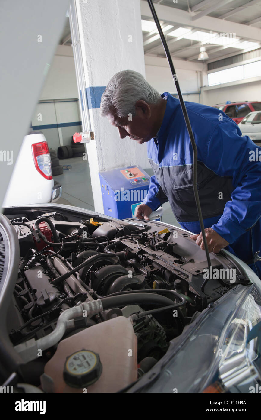 Older Hispanic mechanic examining car in garage Stock Photo - Alamy
