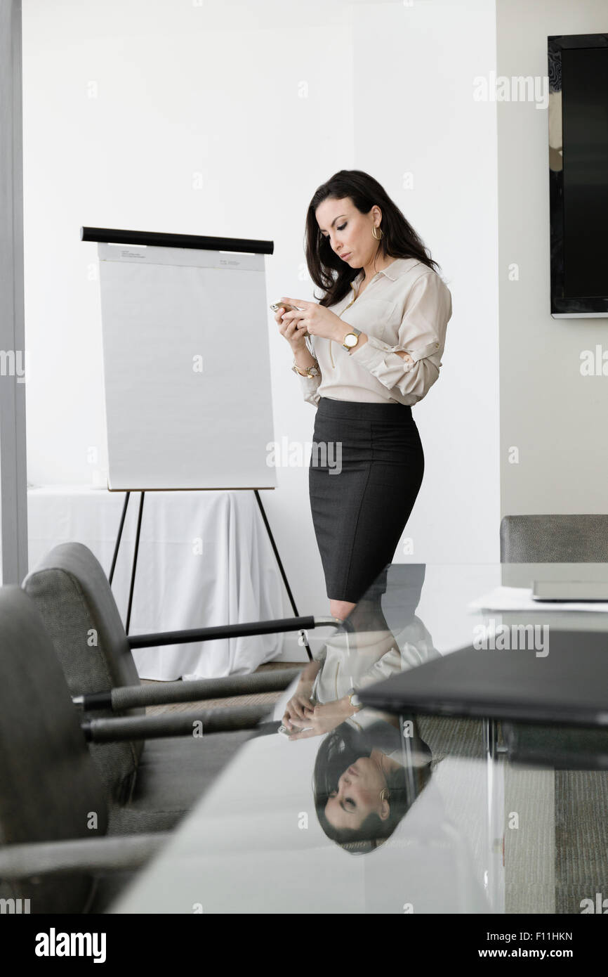 Mixed race businesswoman using cell phone in conference room Stock ...