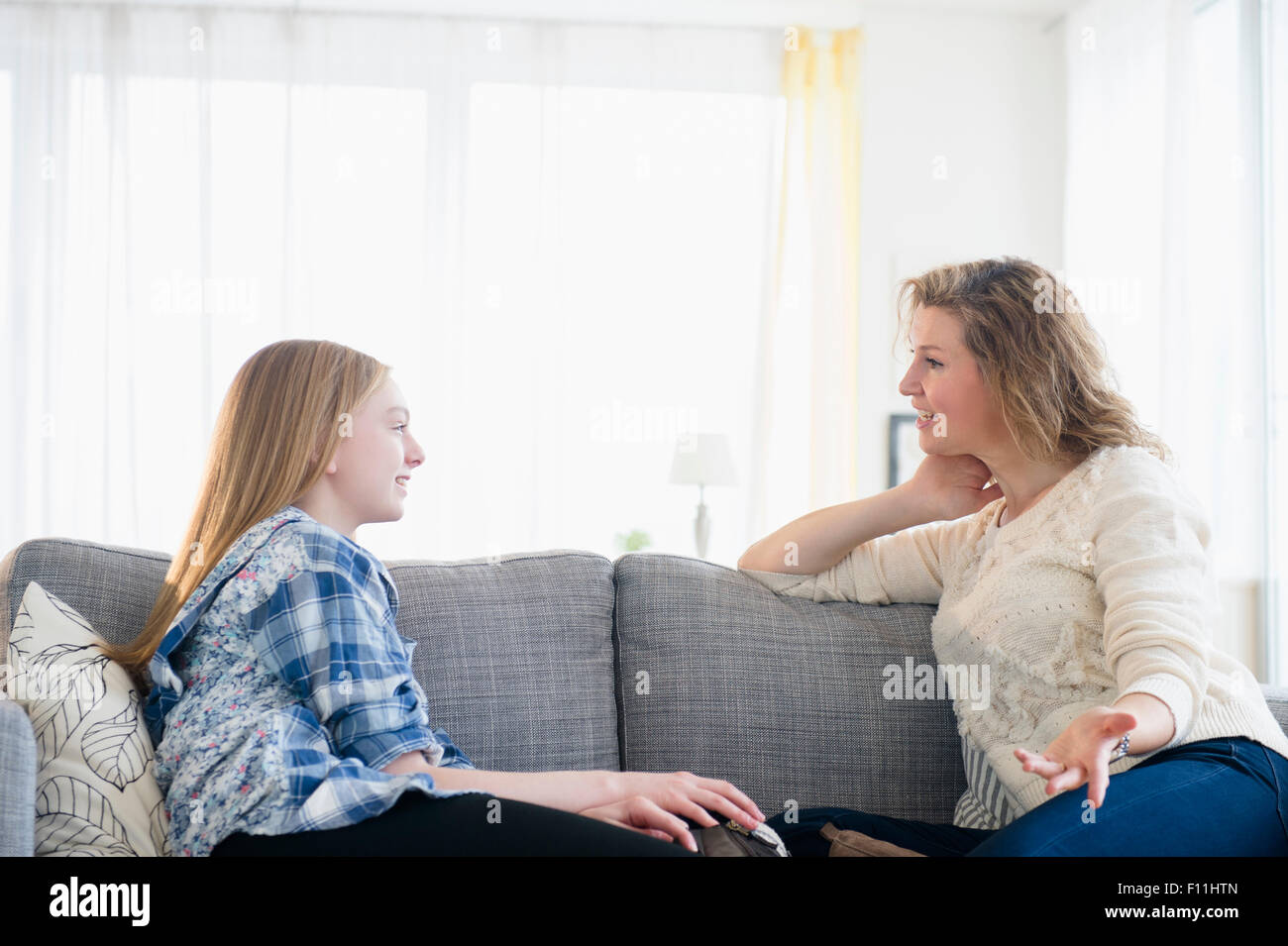 Caucasian mother and daughter talking on sofa Stock Photo - Alamy