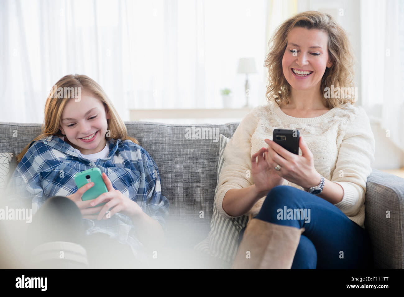 Caucasian mother and daughter using cell phones on sofa Stock Photo - Alamy