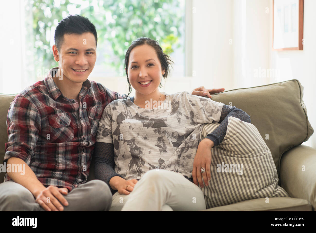 Couple smiling on sofa in living room Stock Photo - Alamy