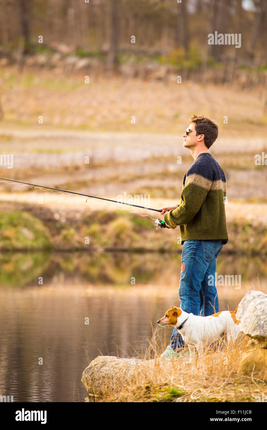 Caucasian man fishing with dog in remote lake Stock Photo - Alamy