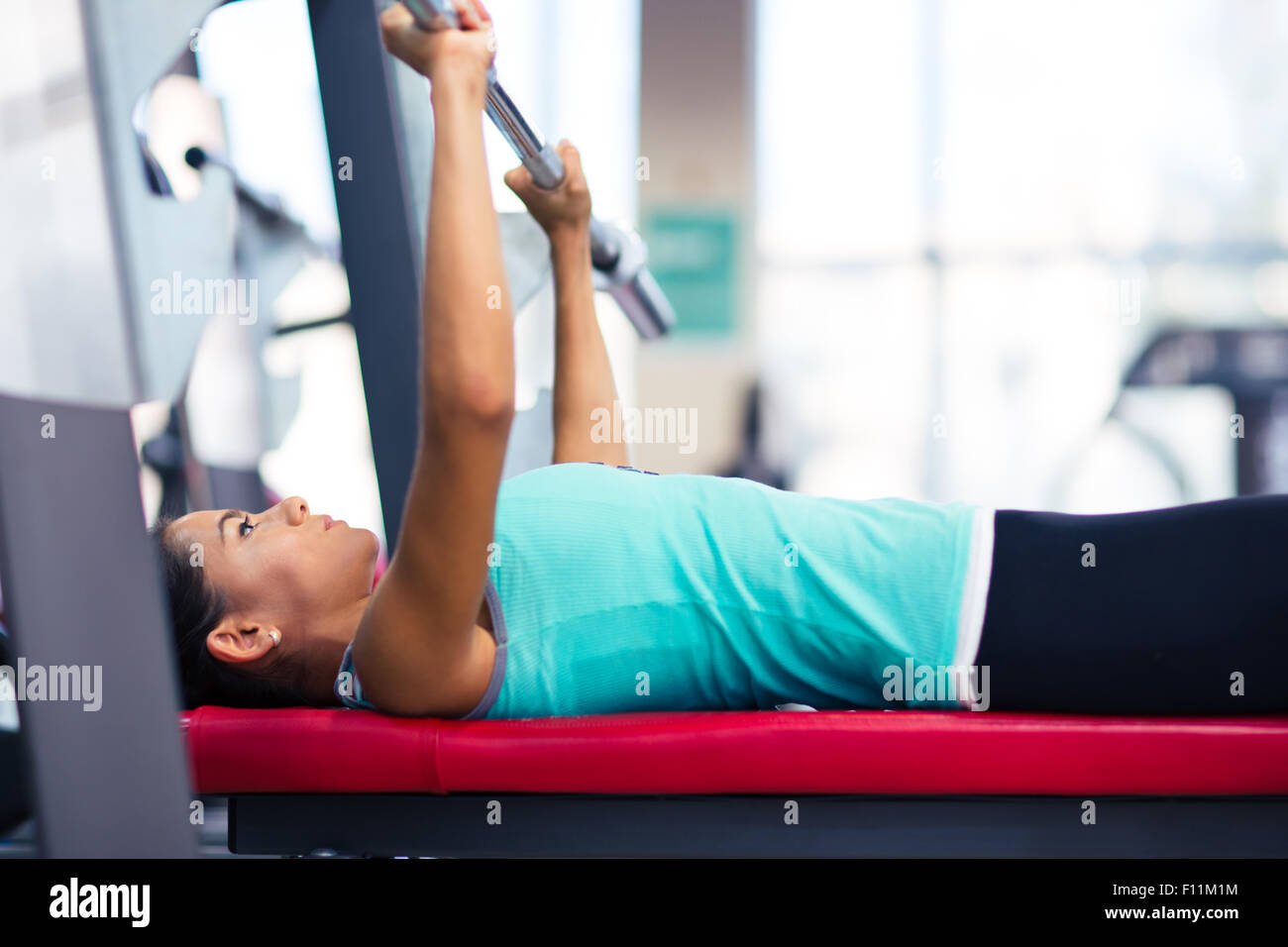 Beautiful woman work out with barbell on the bench in fitness gym Stock ...