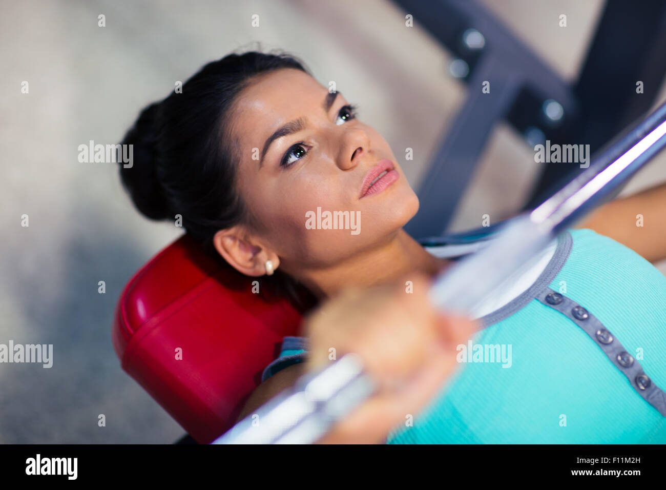 Young sports woman workout with barbell on the bench in fitness gym ...