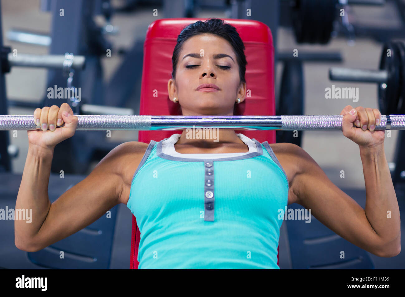 Beautiful woman lifting barbell on the bench in fitness gym Stock Photo ...