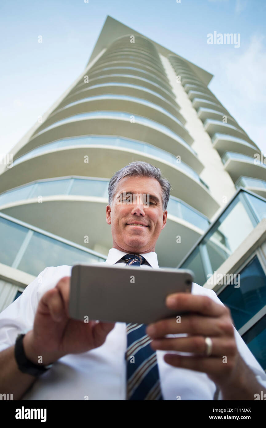 Low angle view of Caucasian businessman using cell phone at high rise ...