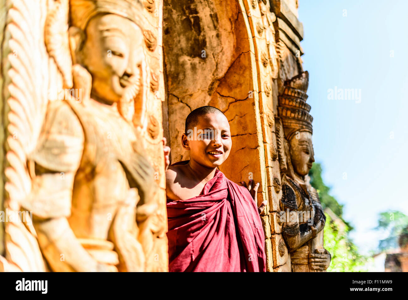 Asian monk-in-training peering around carved temple walls Stock Photo ...