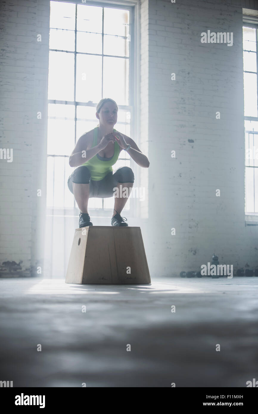 Athlete crouching on platform in gym Stock Photo - Alamy