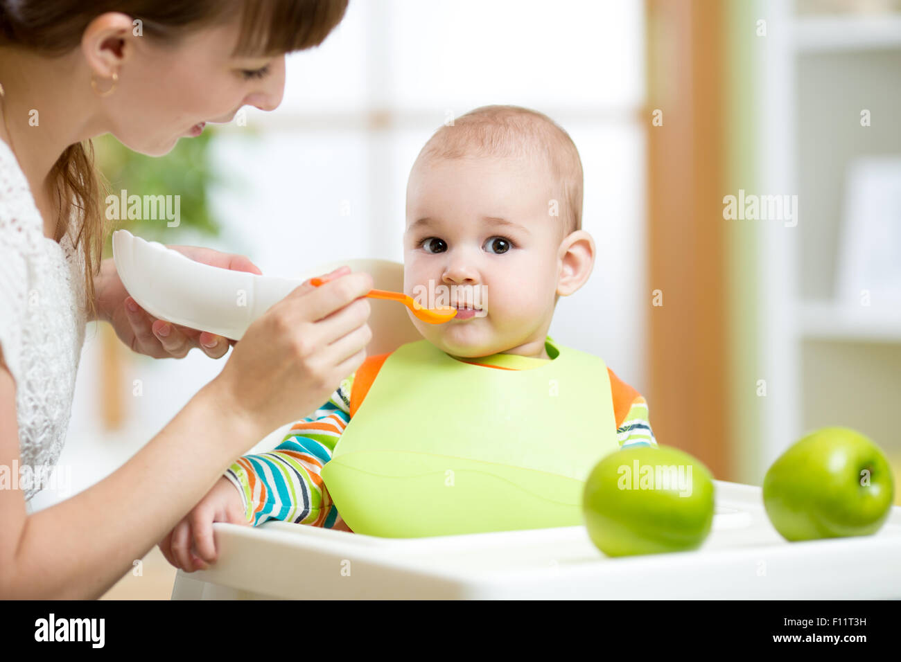 Happy mother spoon feeding her baby child Stock Photo - Alamy