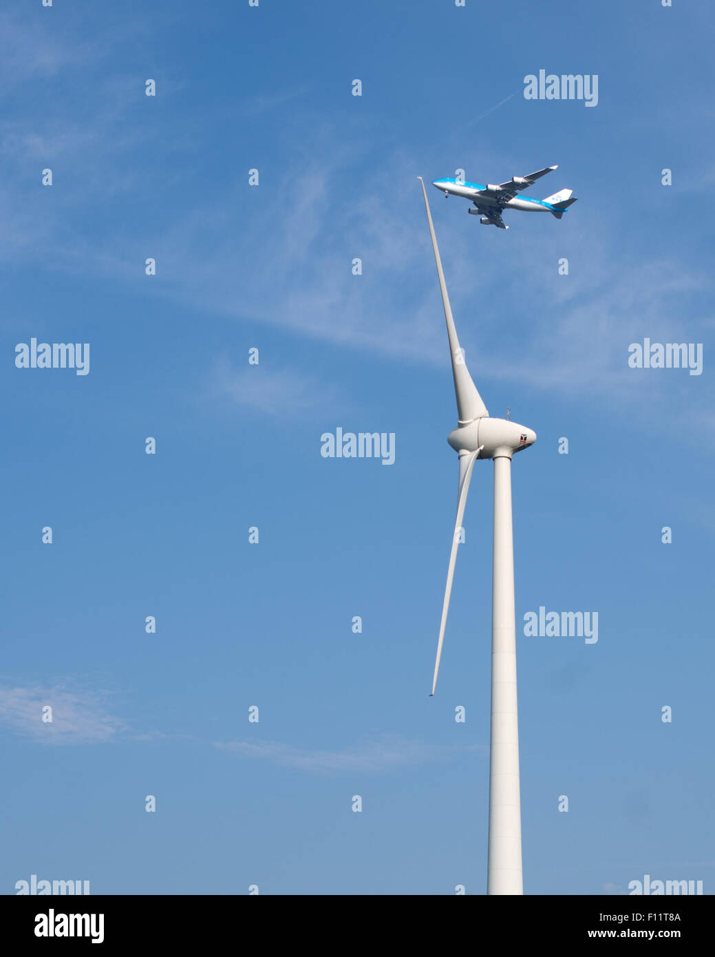 Passenger jet flying over a wind turbine on it`s approach to Schipol ...