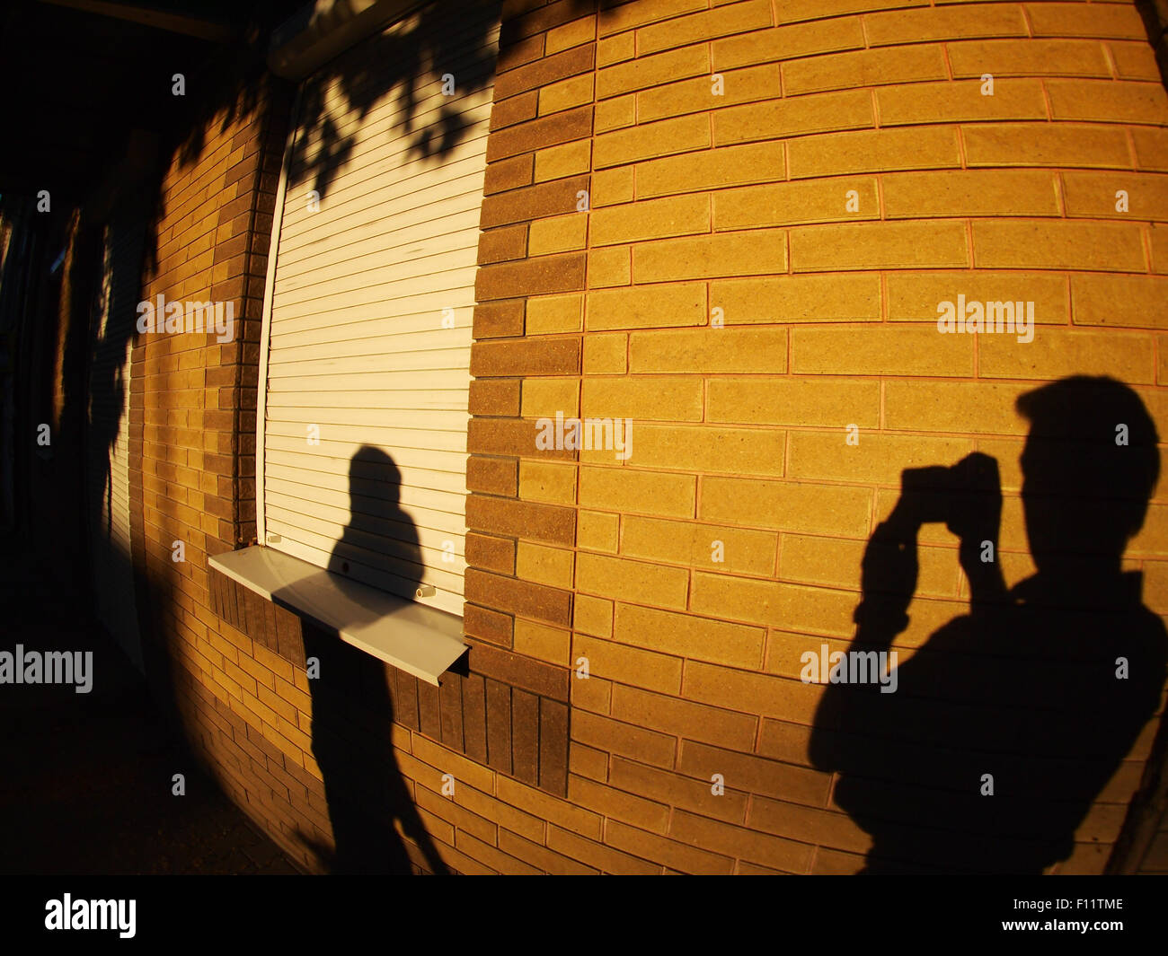 The shadow of a man with a camera on the illuminated wall, who ...