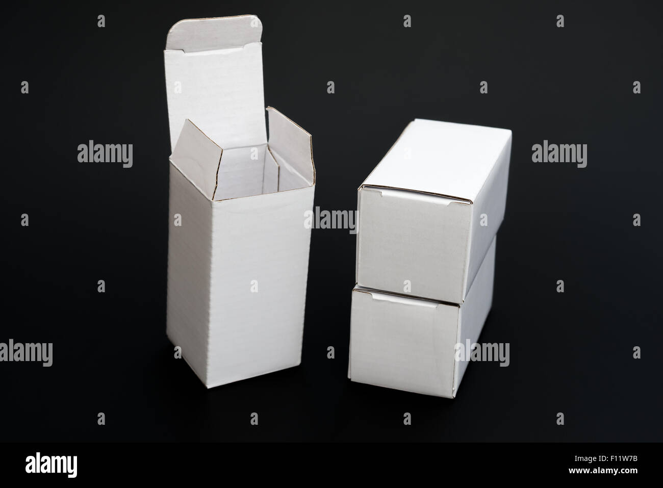 three white boxes with one opened and the other closed on black Stock ...