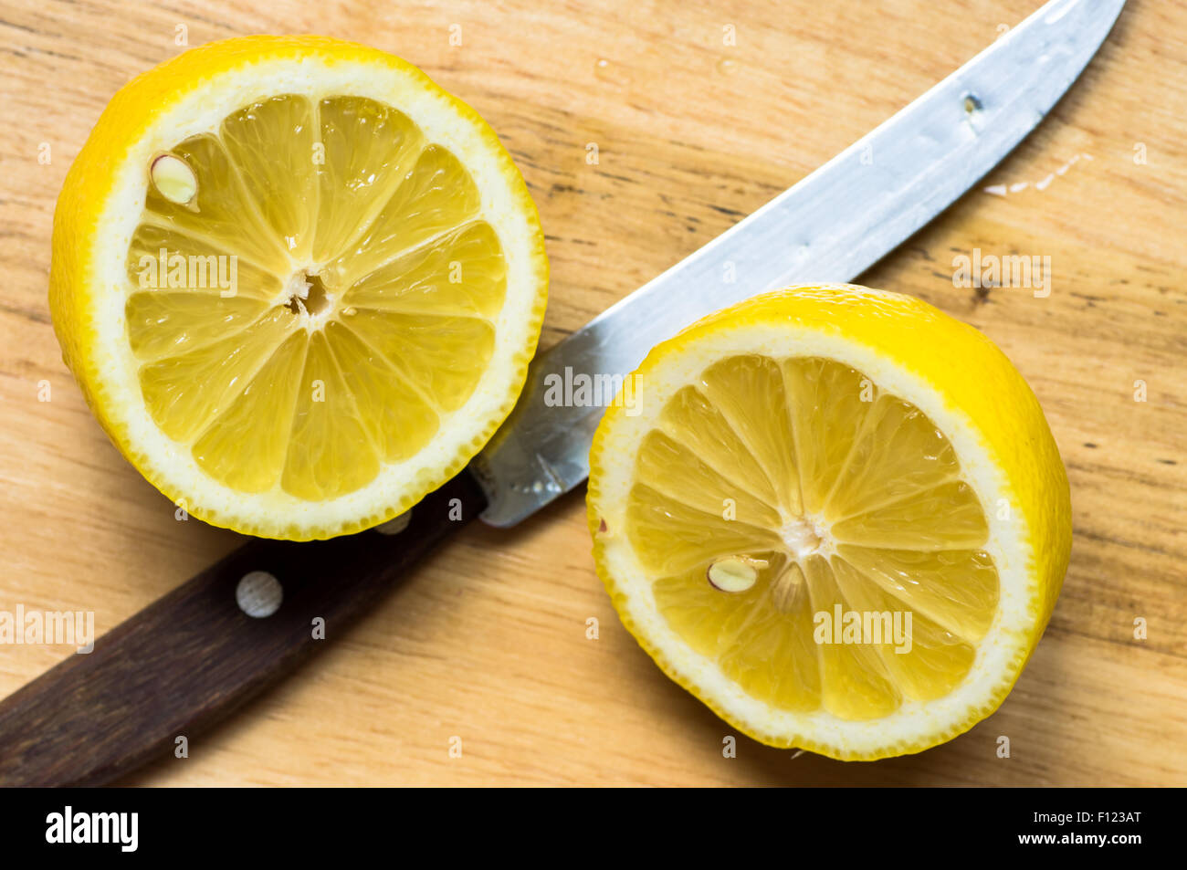 Lemon cut in half with a knife beside Stock Photo - Alamy