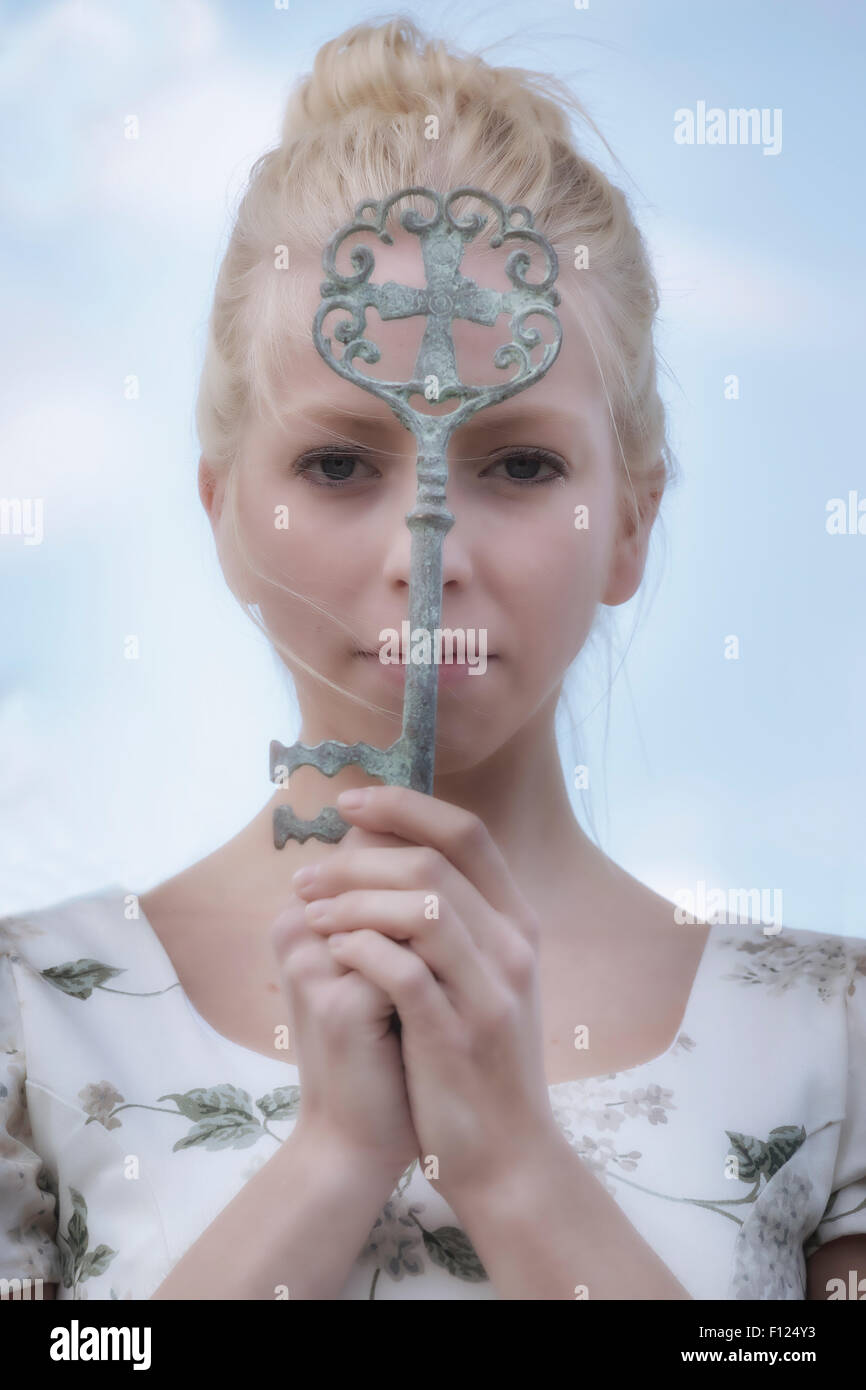 a woman is holding a big, old key in front of her face Stock Photo - Alamy