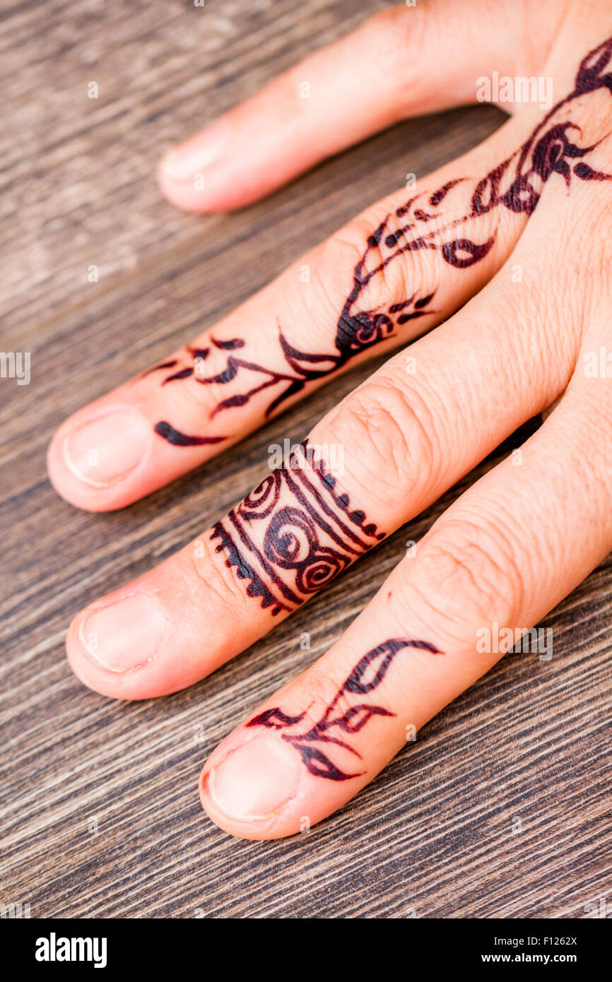 Woman hand without nail polish painted with floral figures using black ...