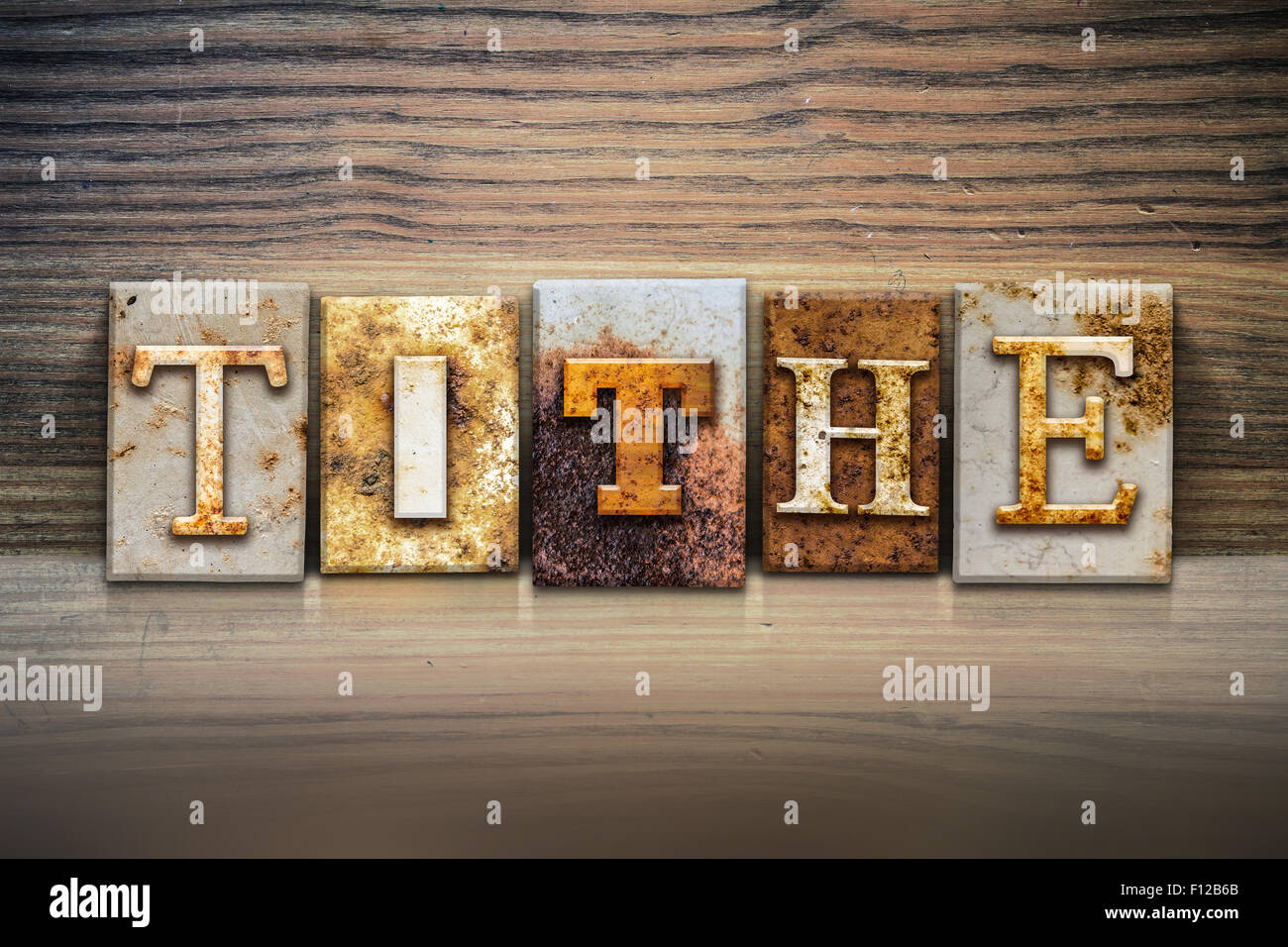 The word "TITHE" written in rusty metal letterpress type sitting on a ...