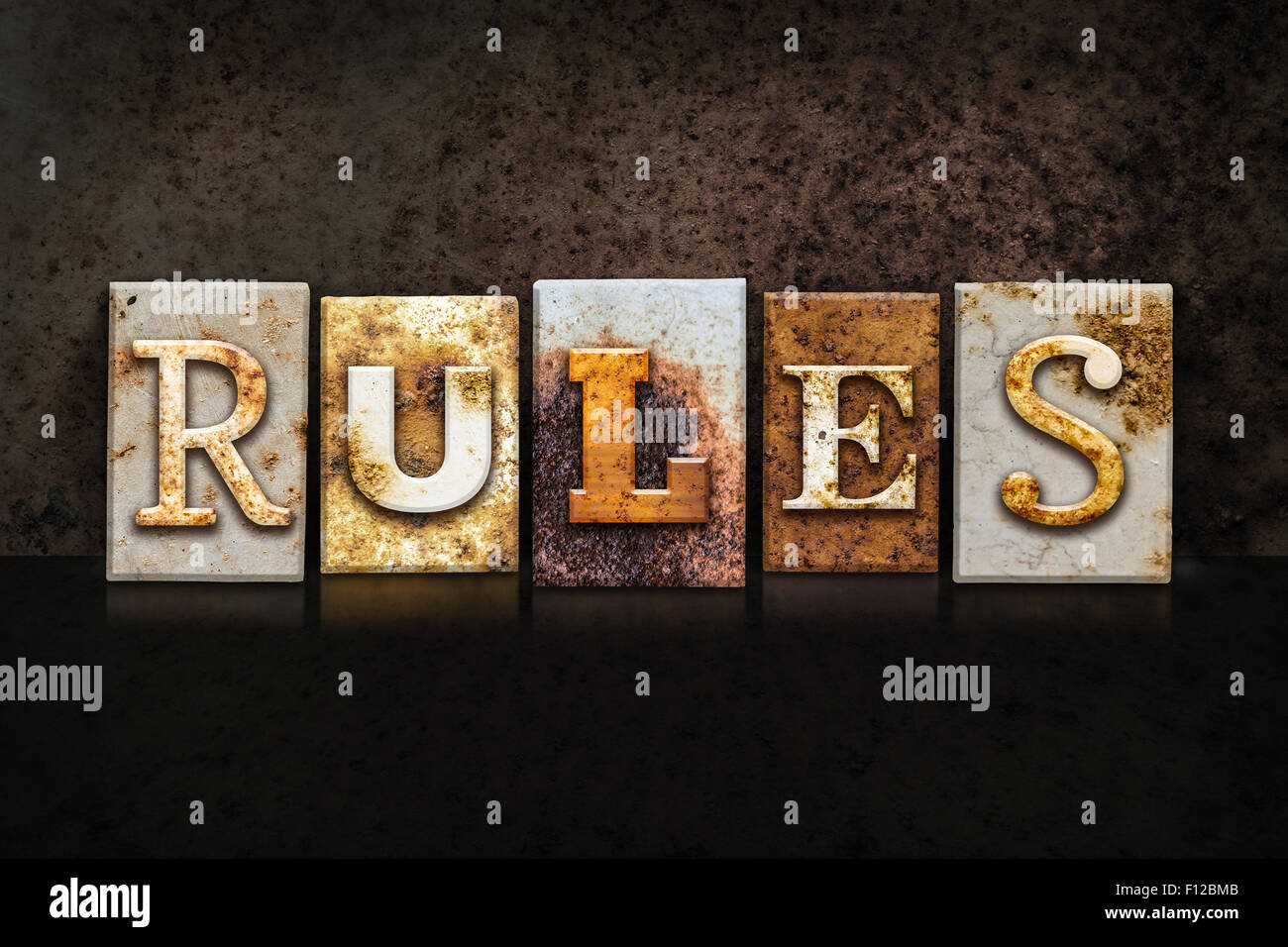 The word "RULES" written in rusty metal letterpress type on a dark ...
