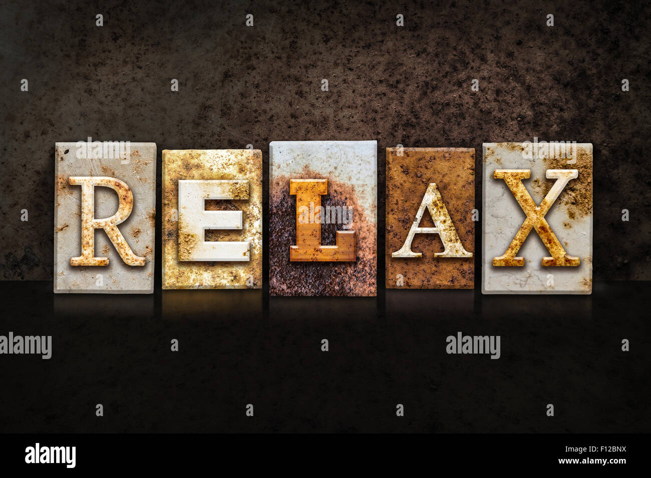 The word "RELAX" written in rusty metal letterpress type on a dark ...