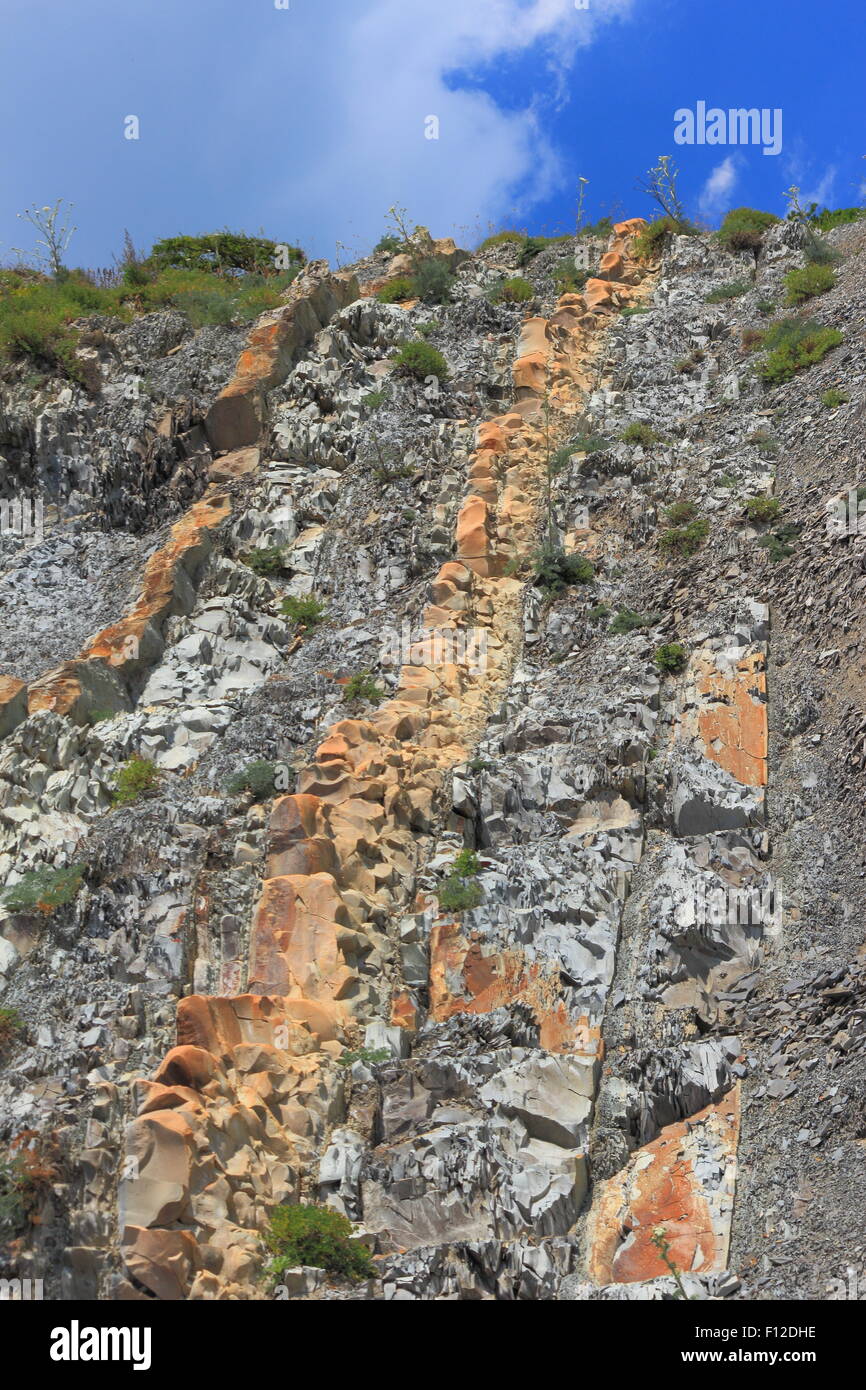 Coastal steep mountain slope with visible rock strata with a background ...