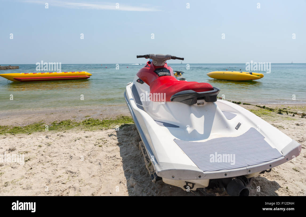 Colorful red jet ski beached ashore on a sandy beach waiting to be ...