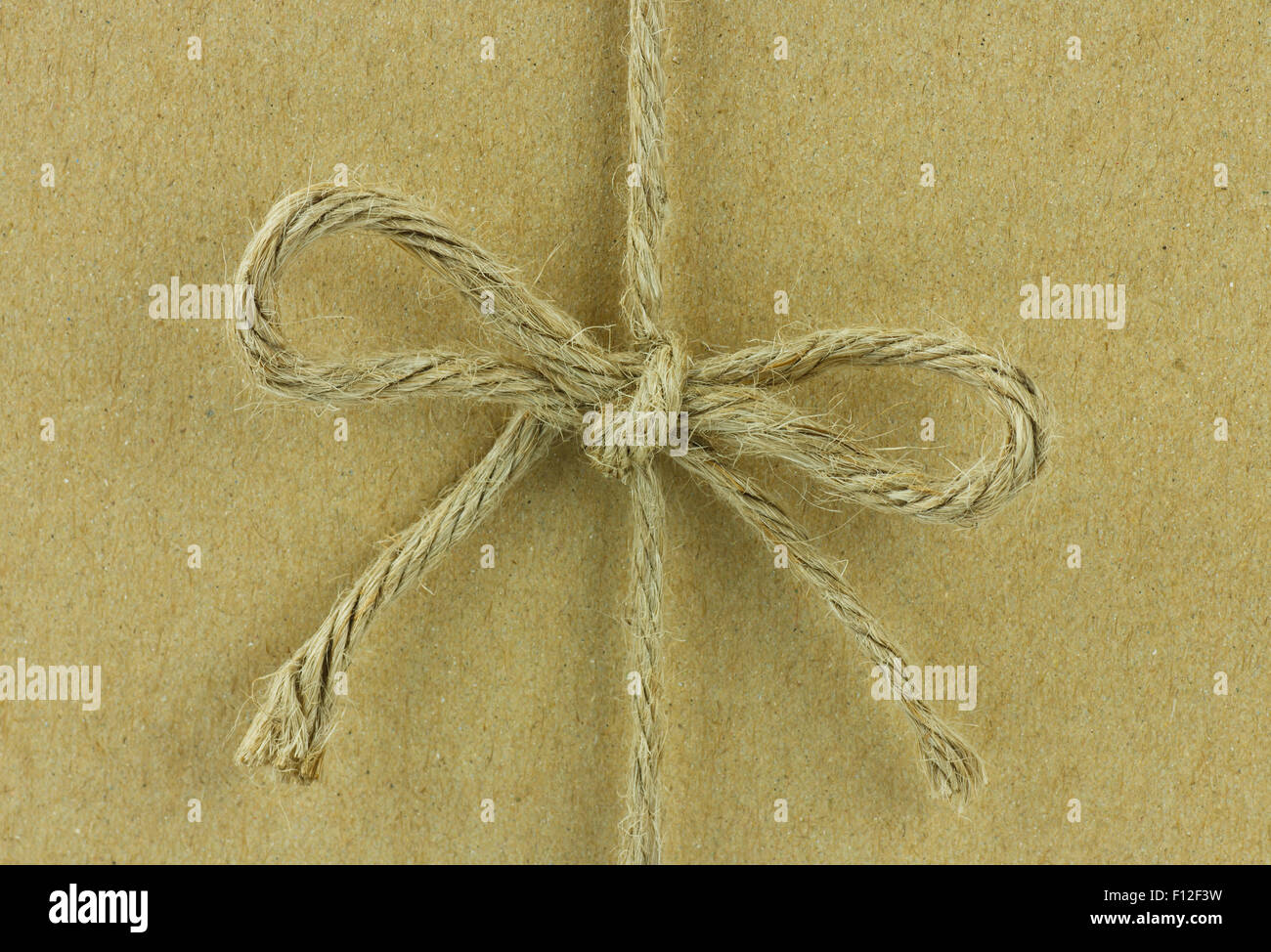 String tied in a bow, over brown recycled paper Stock Photo - Alamy